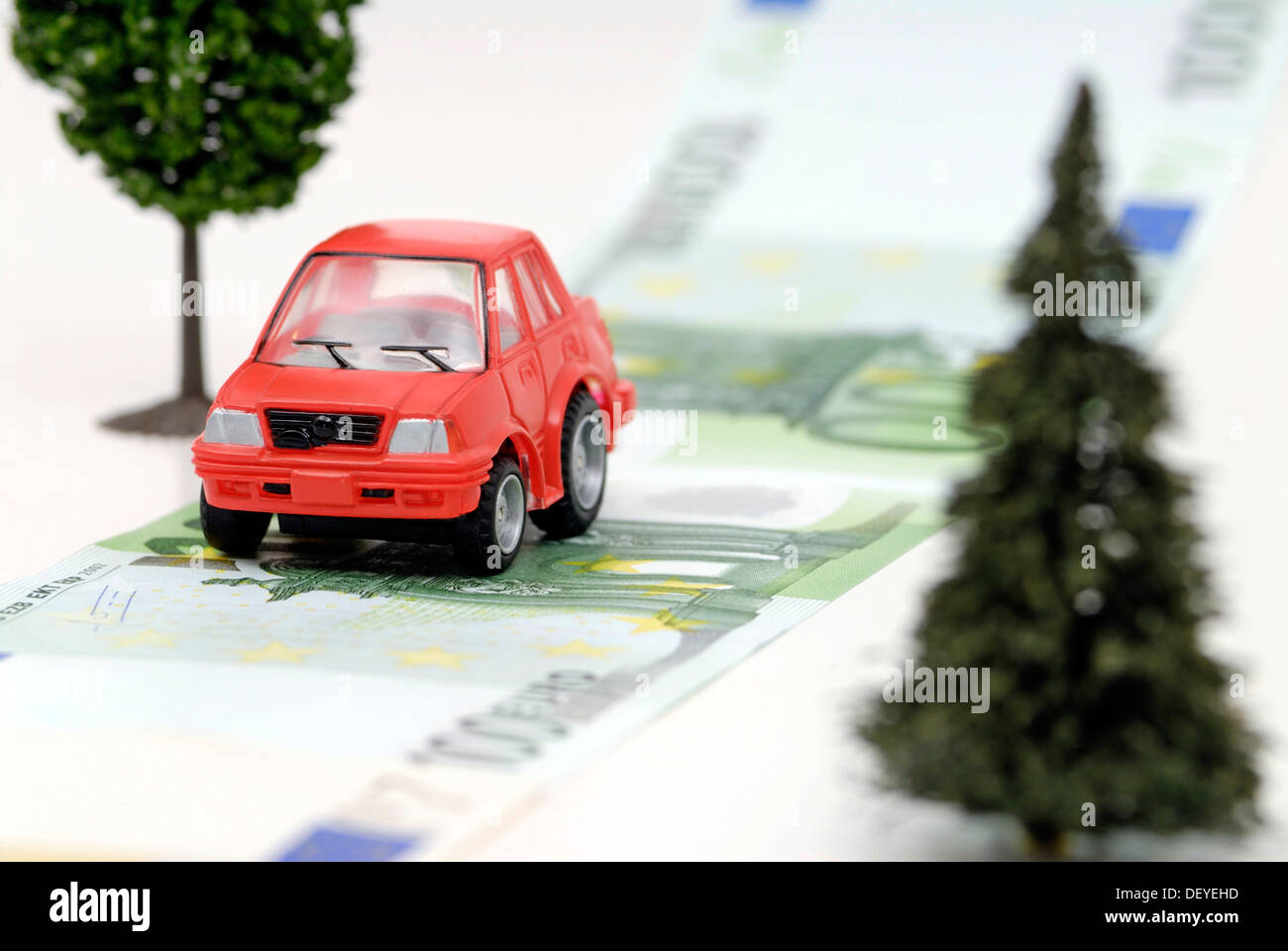 Miniature car driving on a road made of banknotes, symbolic image for ...