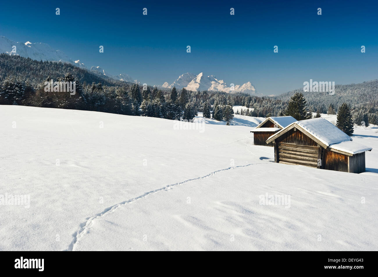 Snow-covered pastures and hay barns, Zugspitze massif at back ...