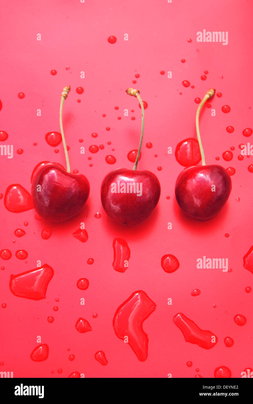 Three red ripe cherries with drops of water Stock Photo - Alamy