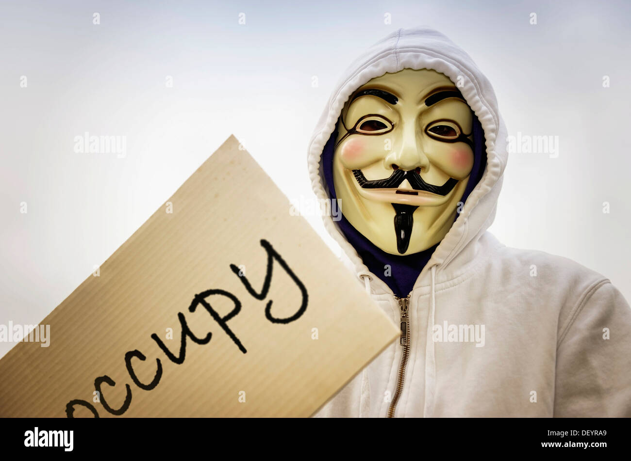 Man wearing the Guy Fawkes mask used by the Occupy movement holding a ...