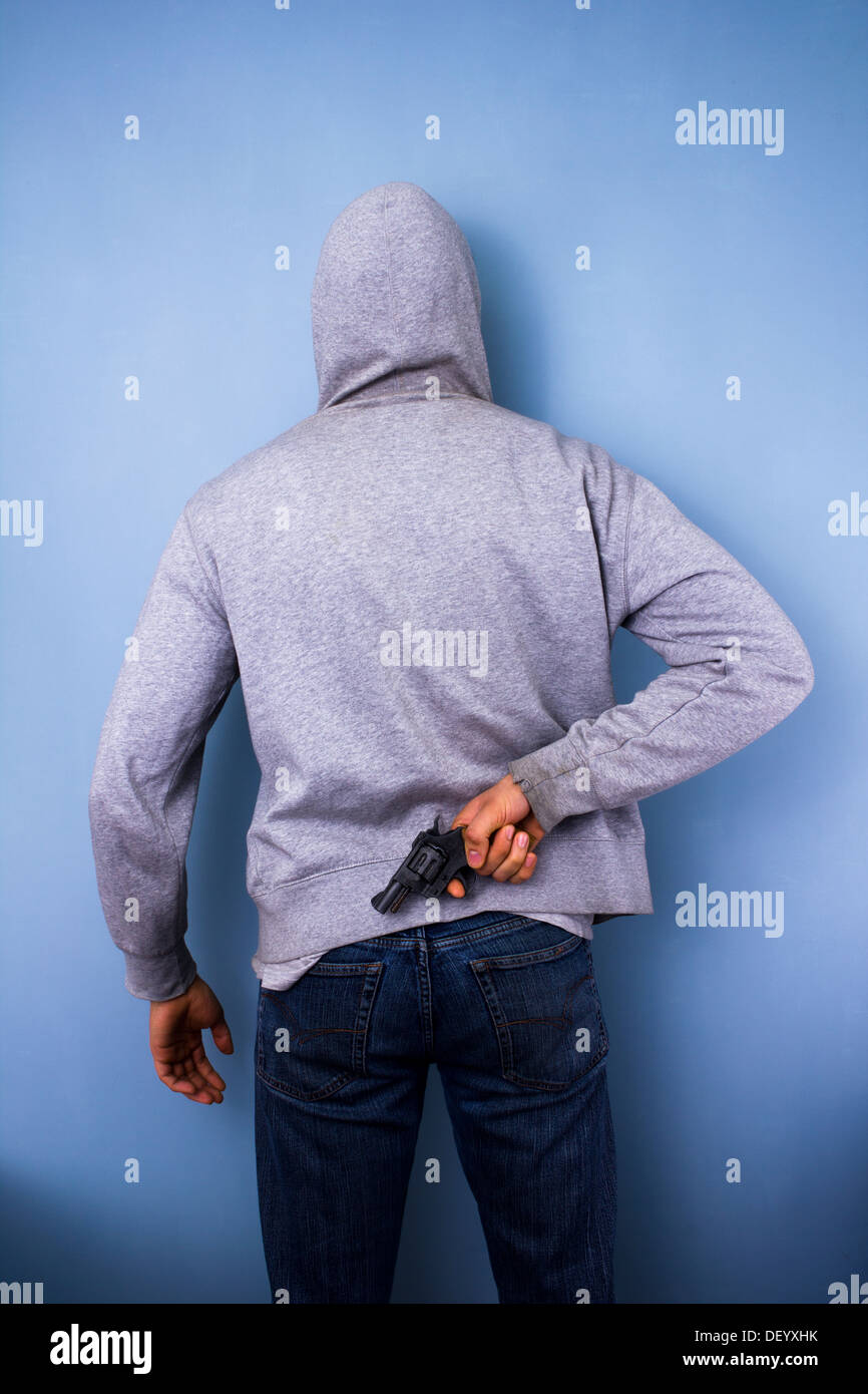 Rear view shot of a hooded man hiding a gun behind his back Stock Photo ...