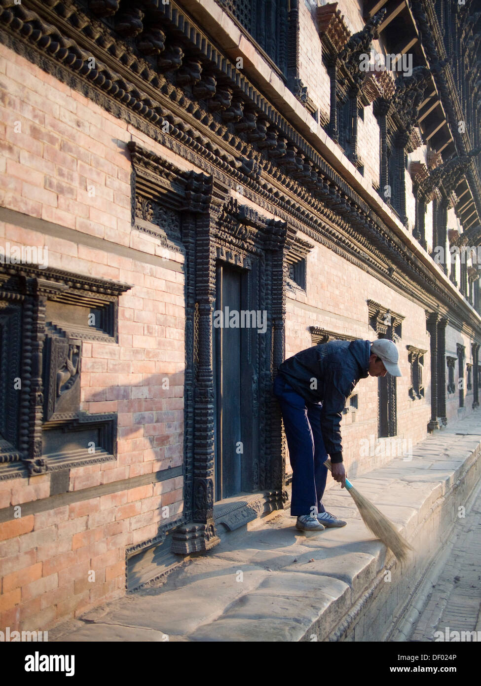 A man sweeps the ledge of a temple entrance in Bhaktapur, Nepal Stock ...