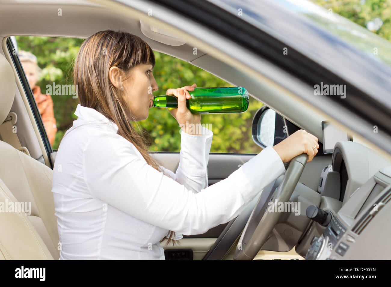 Female motorist drinking and driving while being watched from outside ...