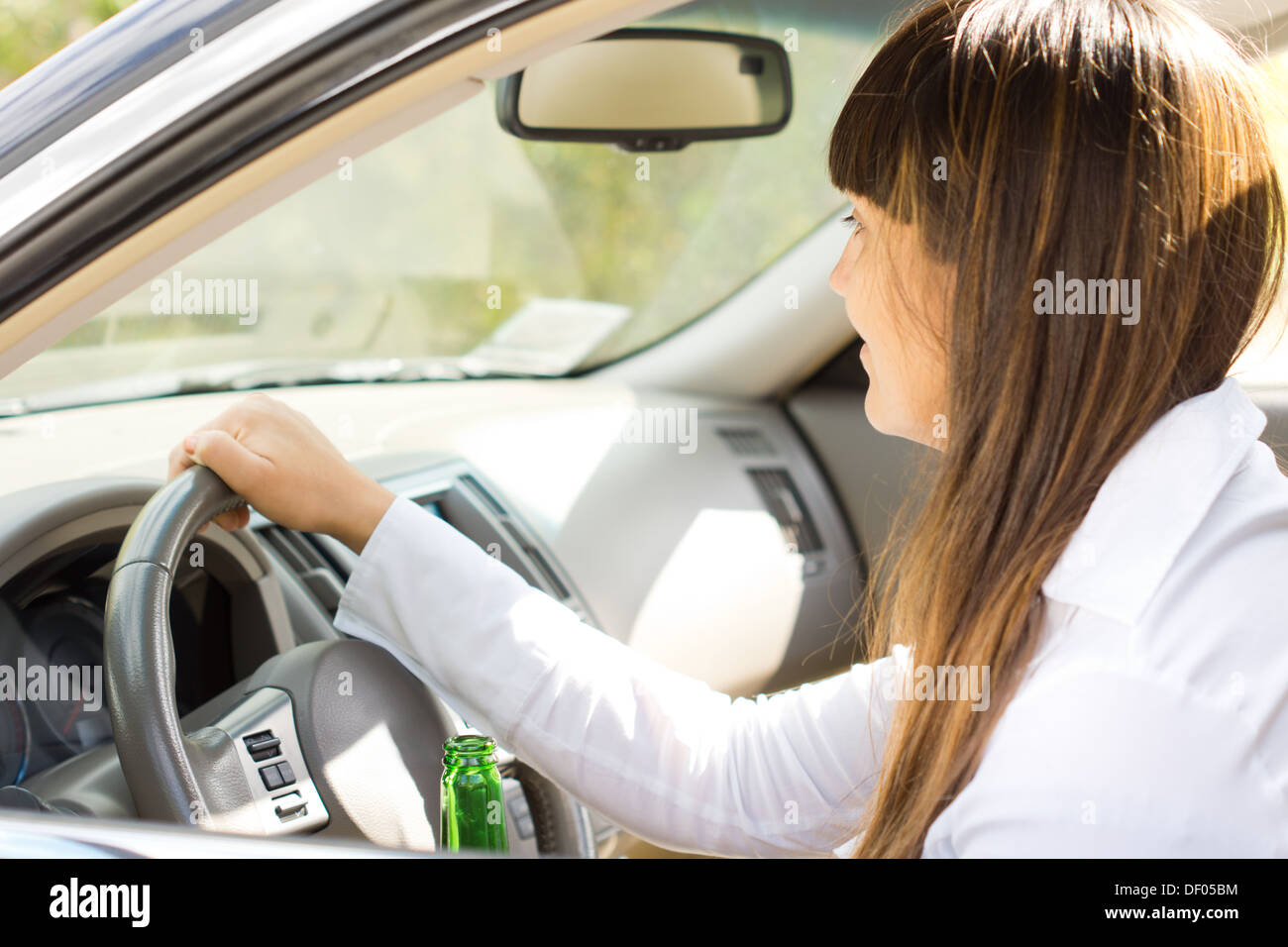 Drunk female motorist grinning as she drives with one hand on the ...
