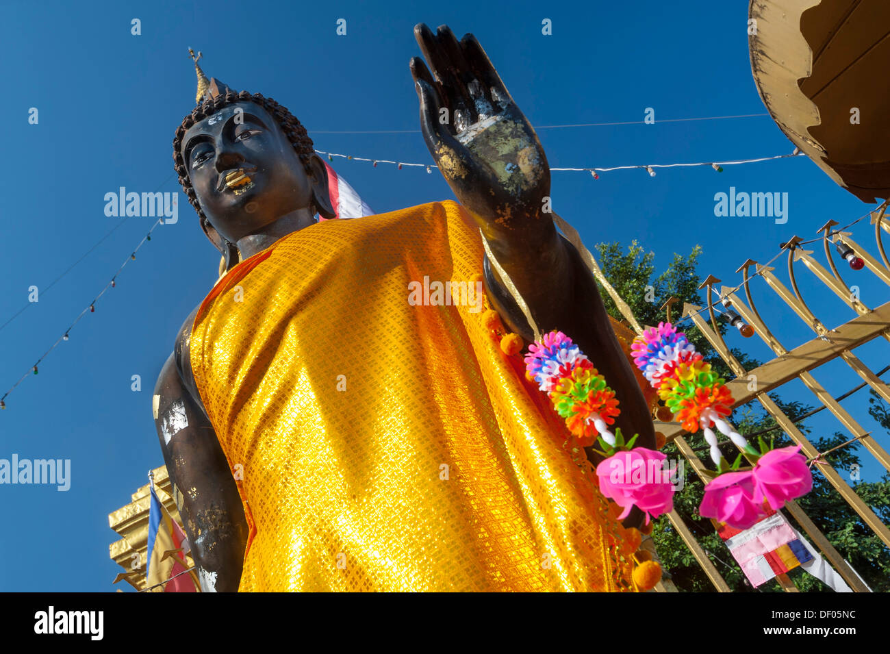 Upright golden Buddha statue in front of the golden pagoda or Chedi ...