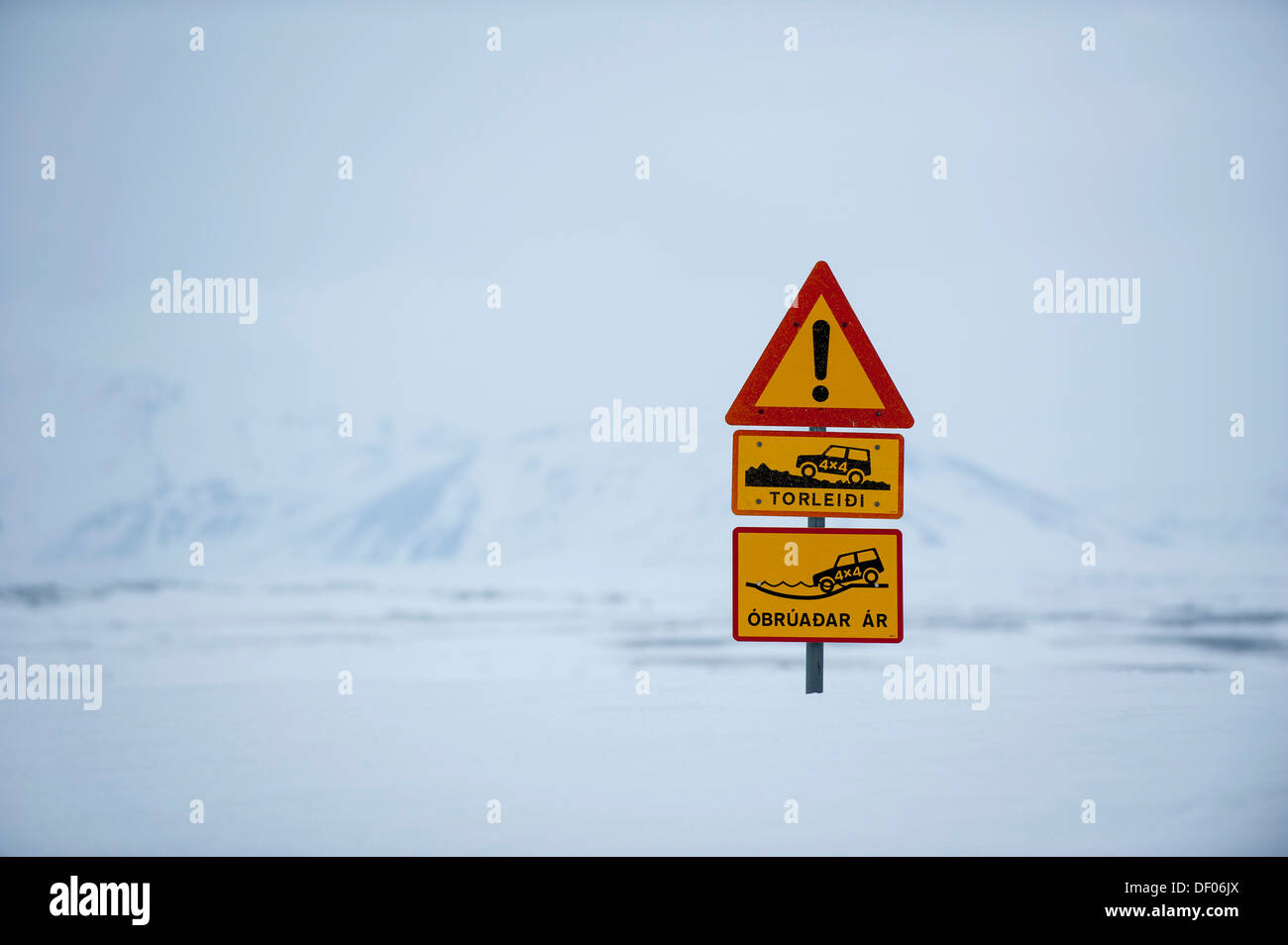 Snow-covered warning sign indicating a ford in the winter landscape ...