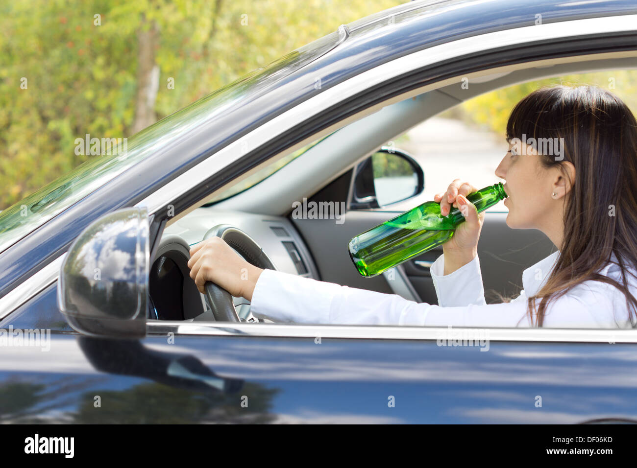 Inebriated female driver drinking alcohol directly from the bottle as ...