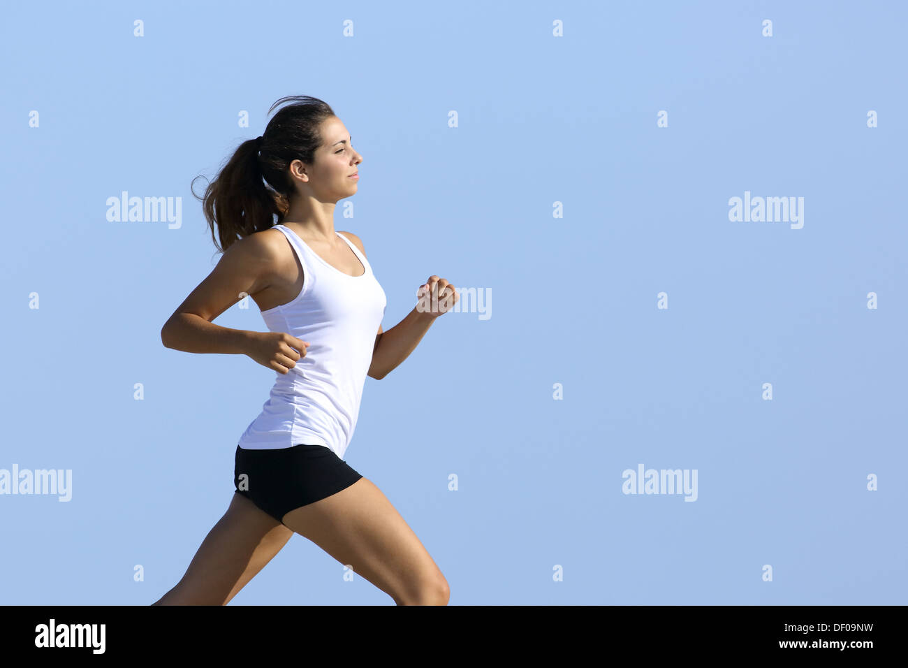 Side view of a fitness woman running fast with the sky in the ...