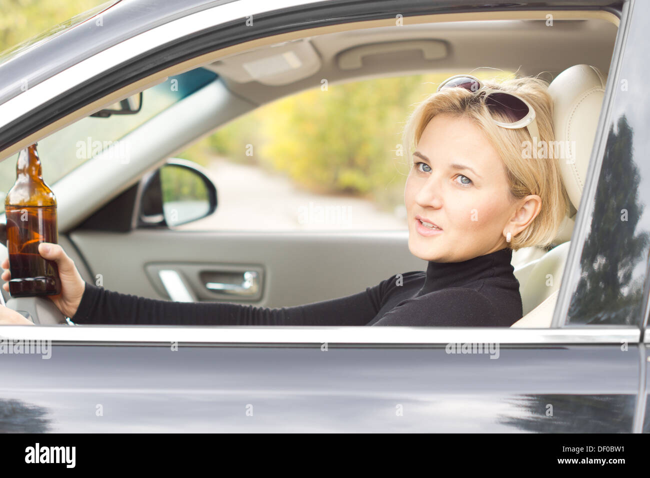 Stylish female drunkard holding her bottle of alcohol as she drives ...