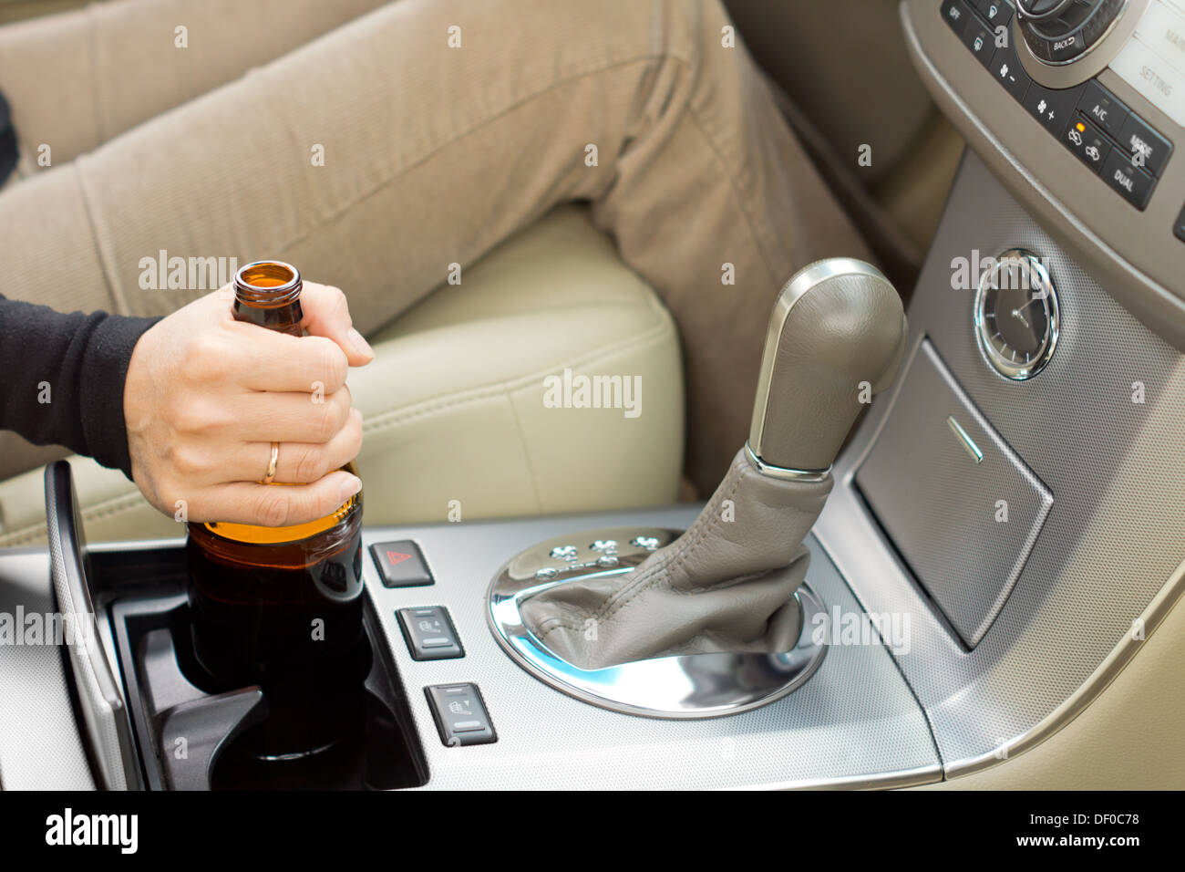 Drunk woman driver holding onto a bottle of alcohol standing in the ...