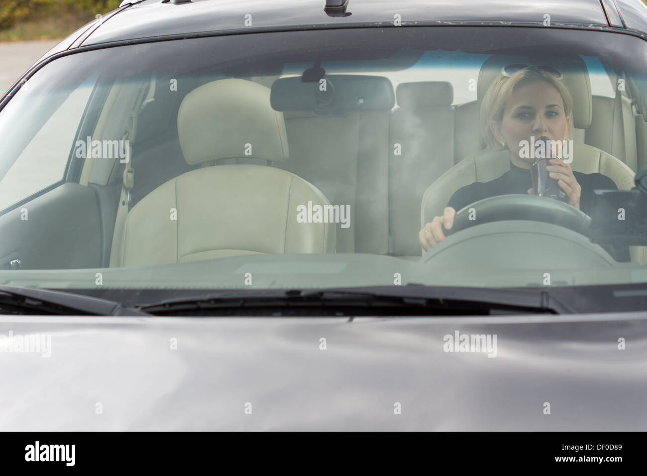 View through the front windscreen of a female driver drinking alcohol ...