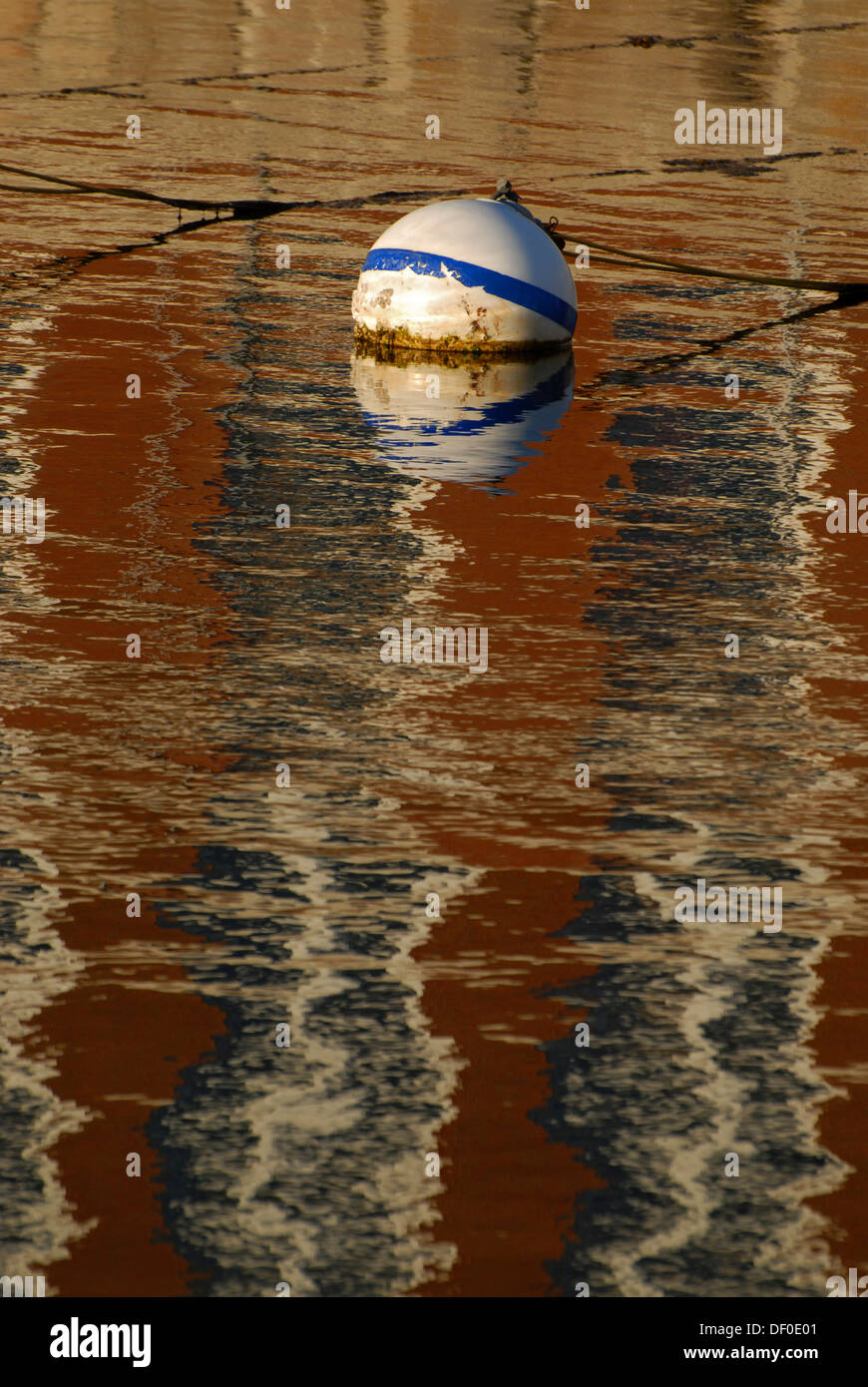 A buoy and the reflections of a red brick building in Eel Pond in Woods ...