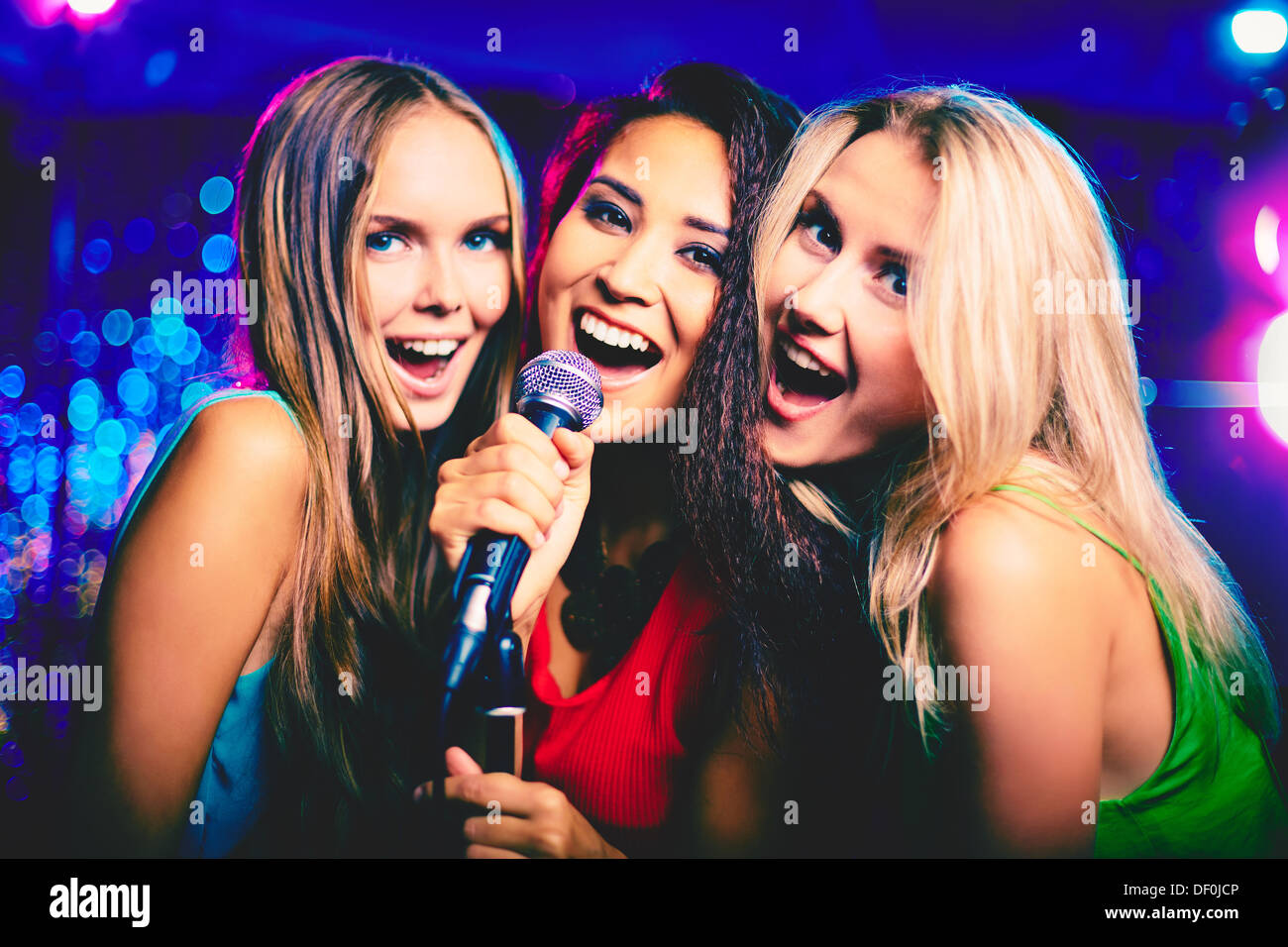 Portrait of happy girls singing in microphone in the karaoke bar Stock ...
