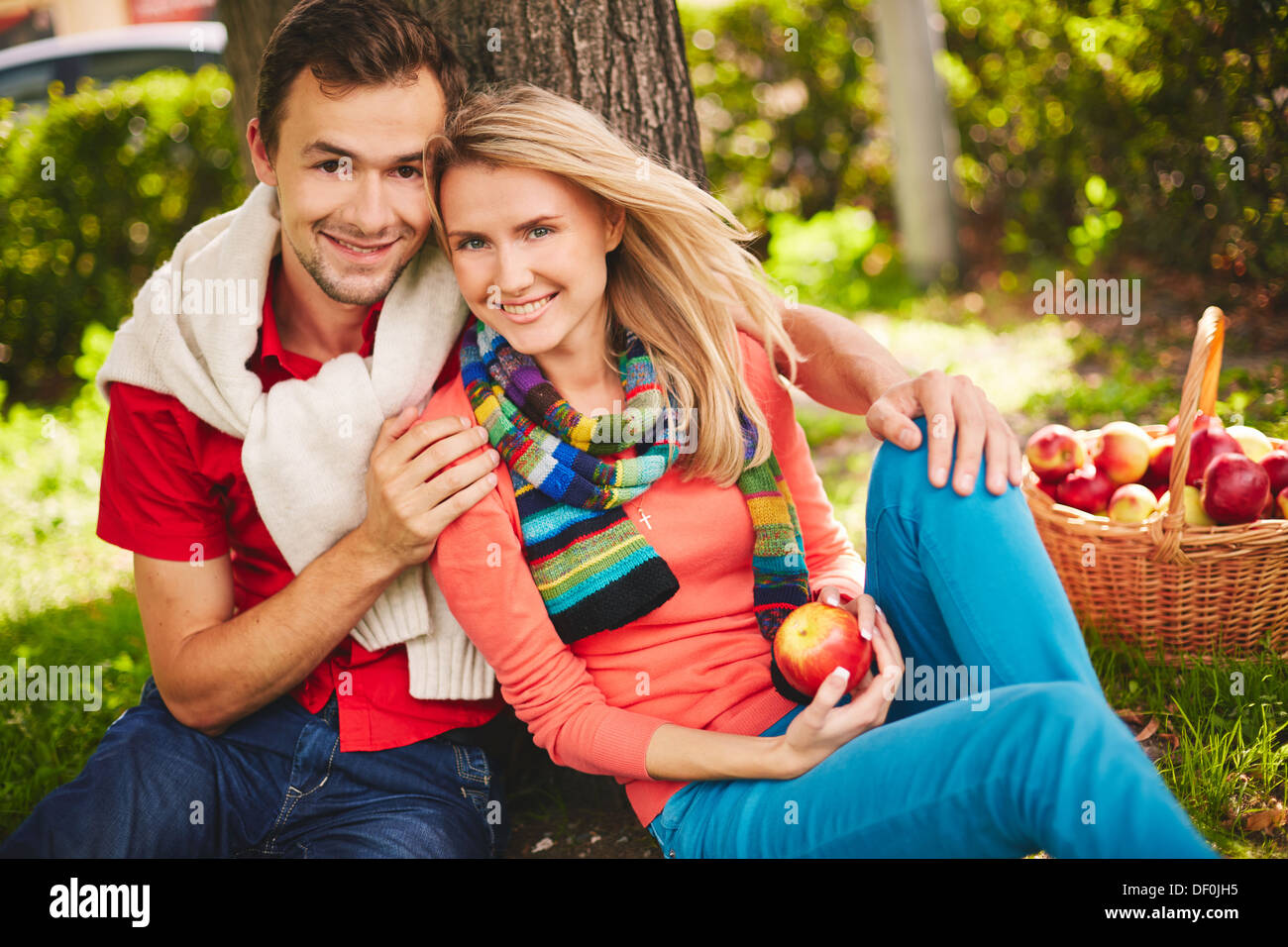 Happy young couple looking at camera in park Stock Photo - Alamy