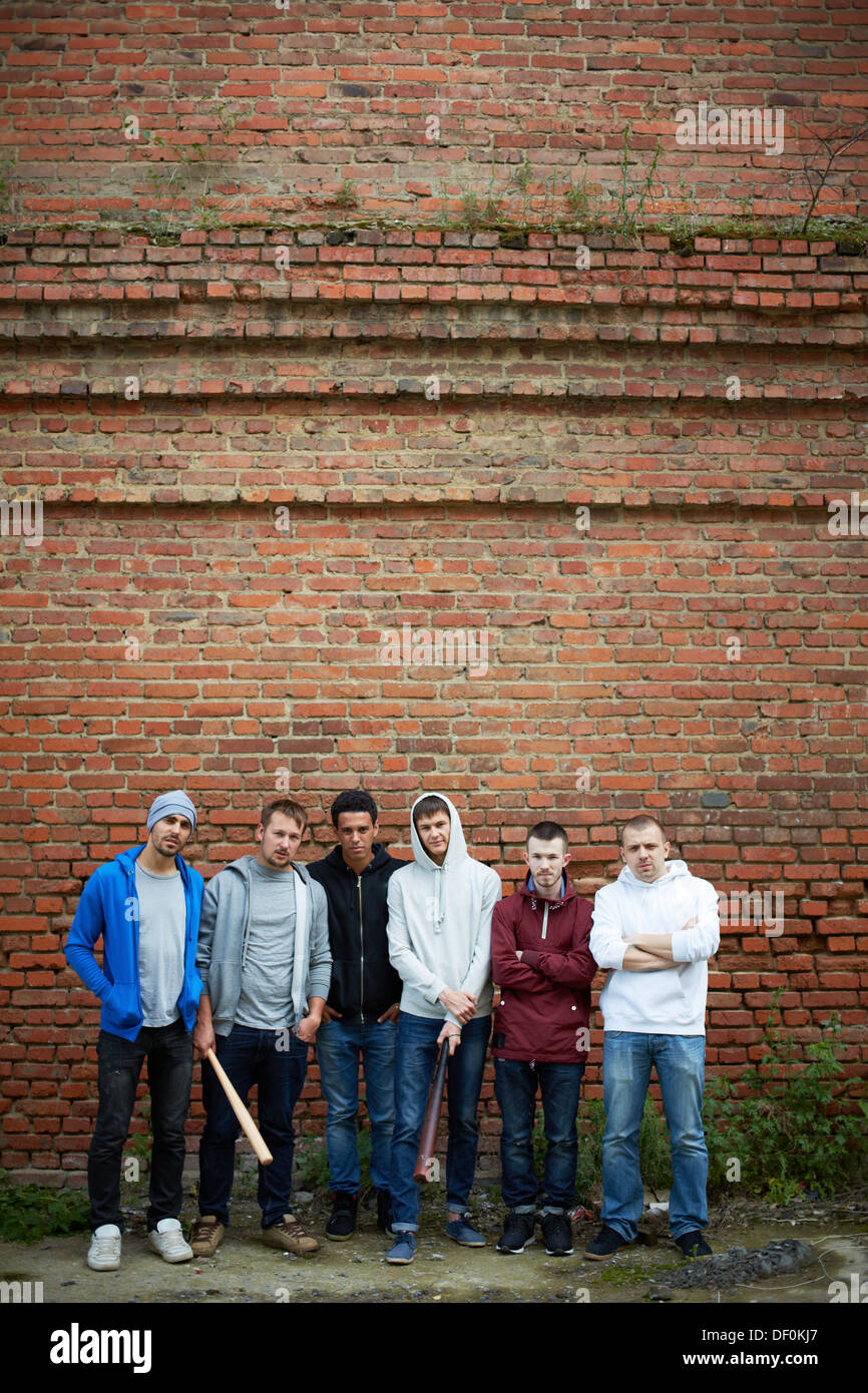 Portrait of several street hooligans or rappers standing against brick ...