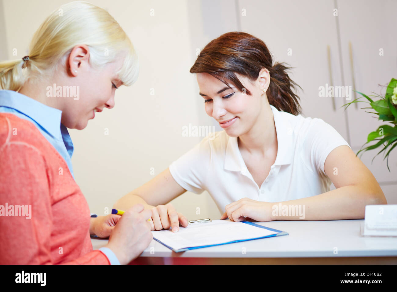 Female patient at doctor filling out and signing forms Stock Photo - Alamy