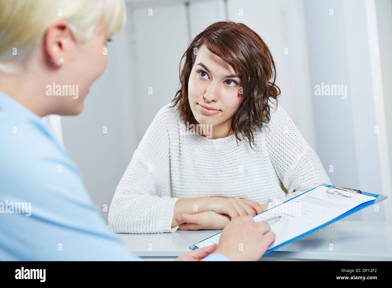 Doctors assistant at reception giving form to female patient to fill ...