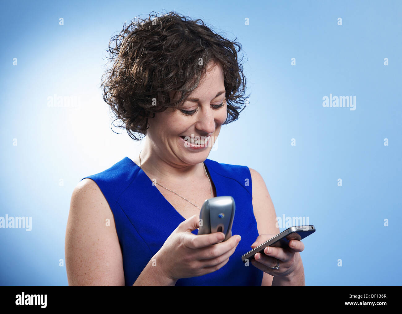Woman smiling while using 2 phones Stock Photo - Alamy