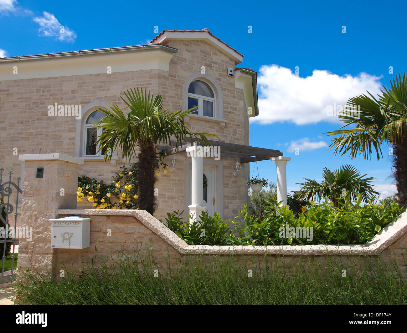stone house yellow roses and palm trees Stock Photo - Alamy