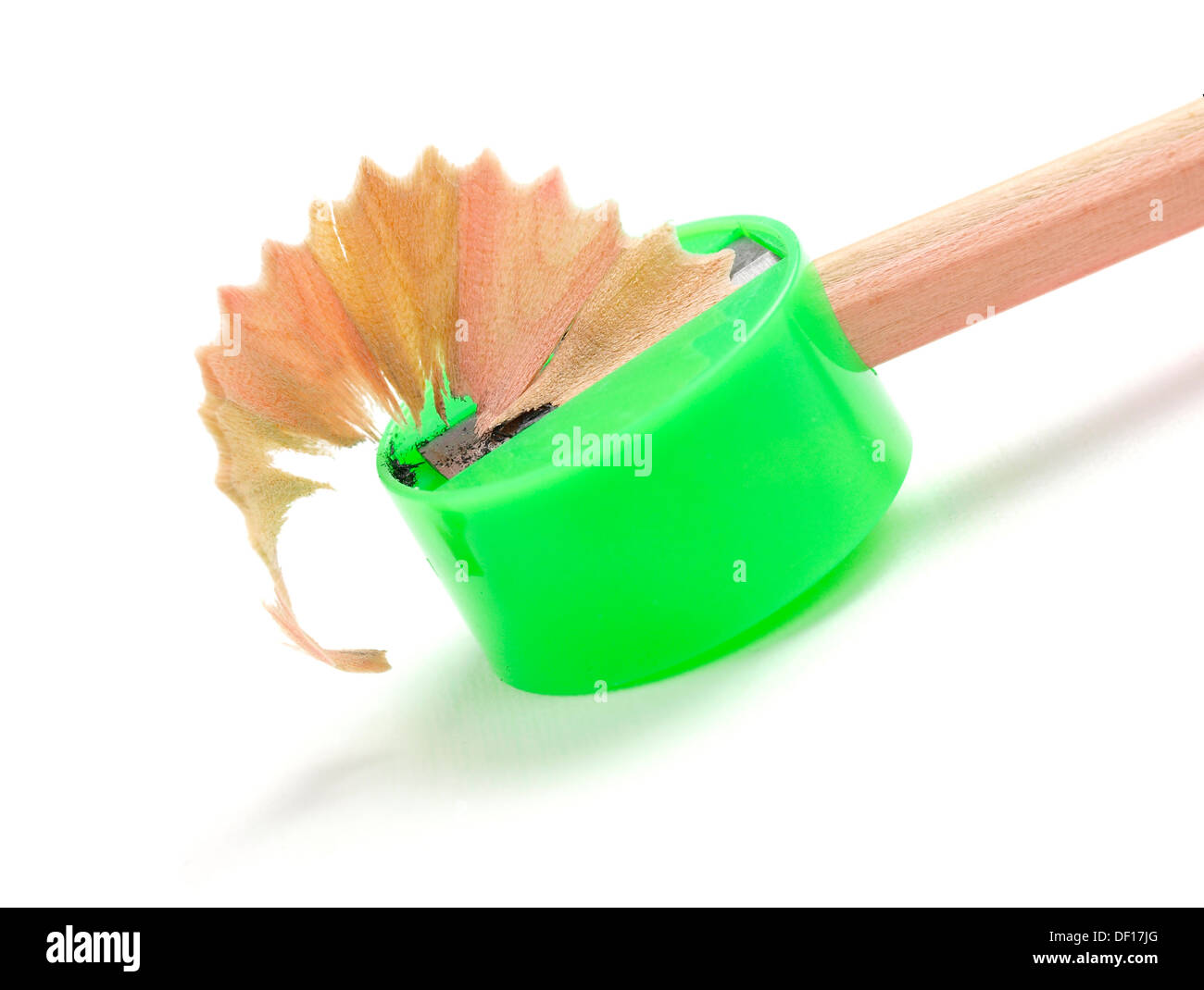 Sharpening a pencil with a green sharpener isolated on white background ...