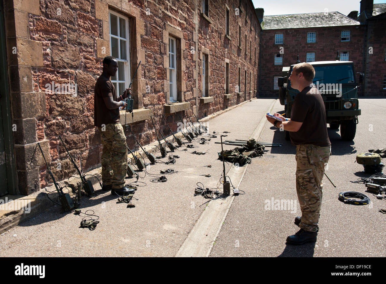 Soldiers with radios and army kit and army lorry at old stone building ...