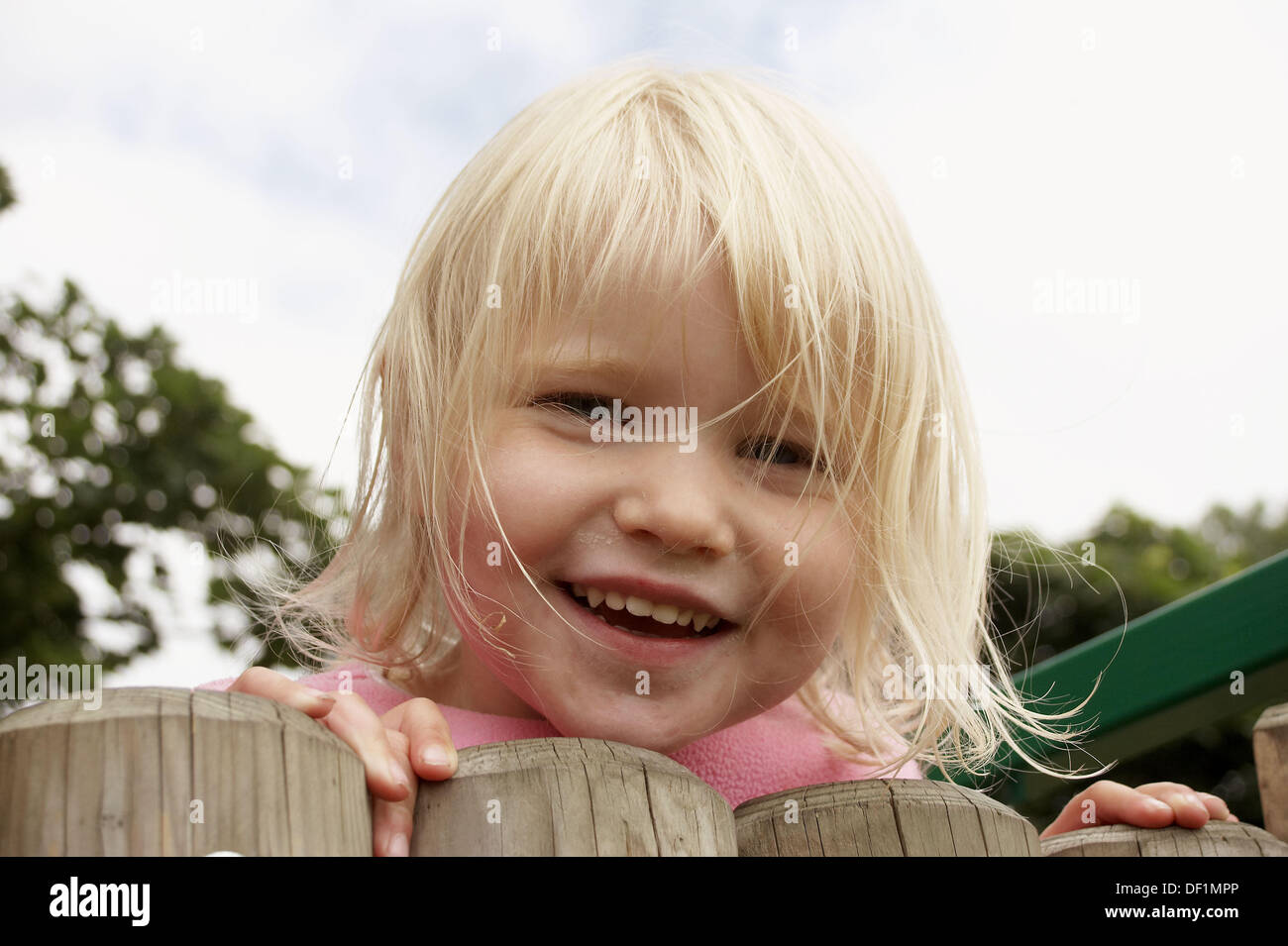 3-year-old-girl-outside-leaning-over-a-fence-smiling-stock-photo-alamy