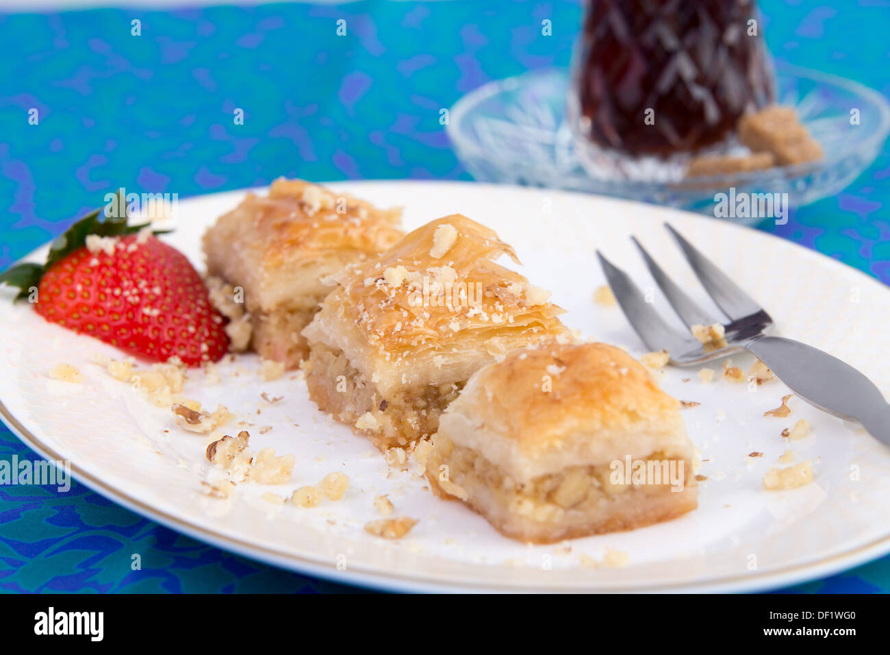 Three pieces of golden color baklava garnished with walnuts and ...