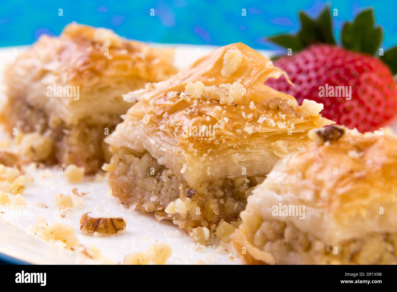 Three pieces of golden color baklava garnished with walnuts and ...