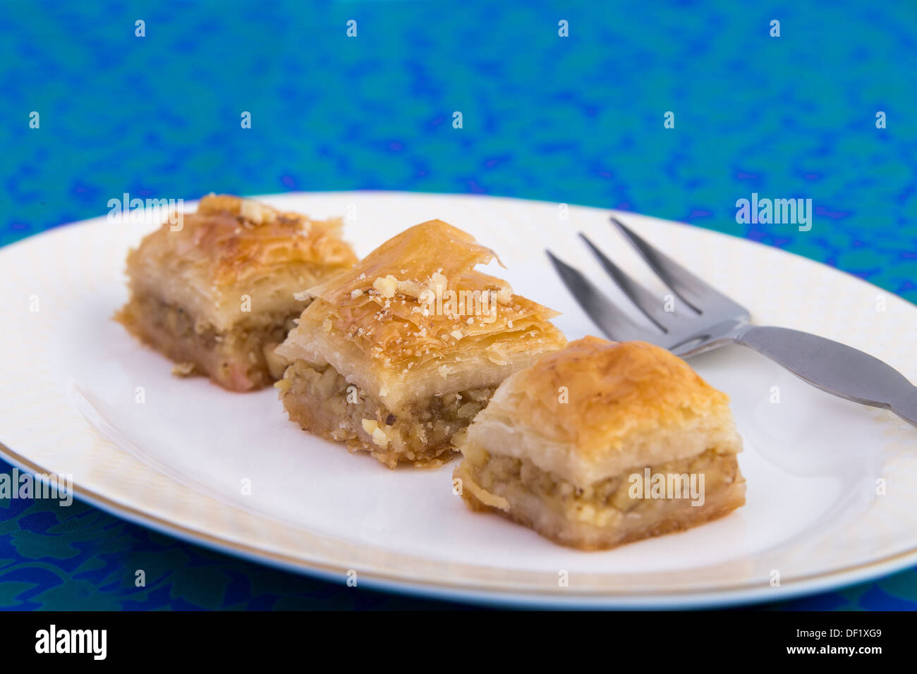 Three pieces of golden color baklava served on oval shape plate on ...