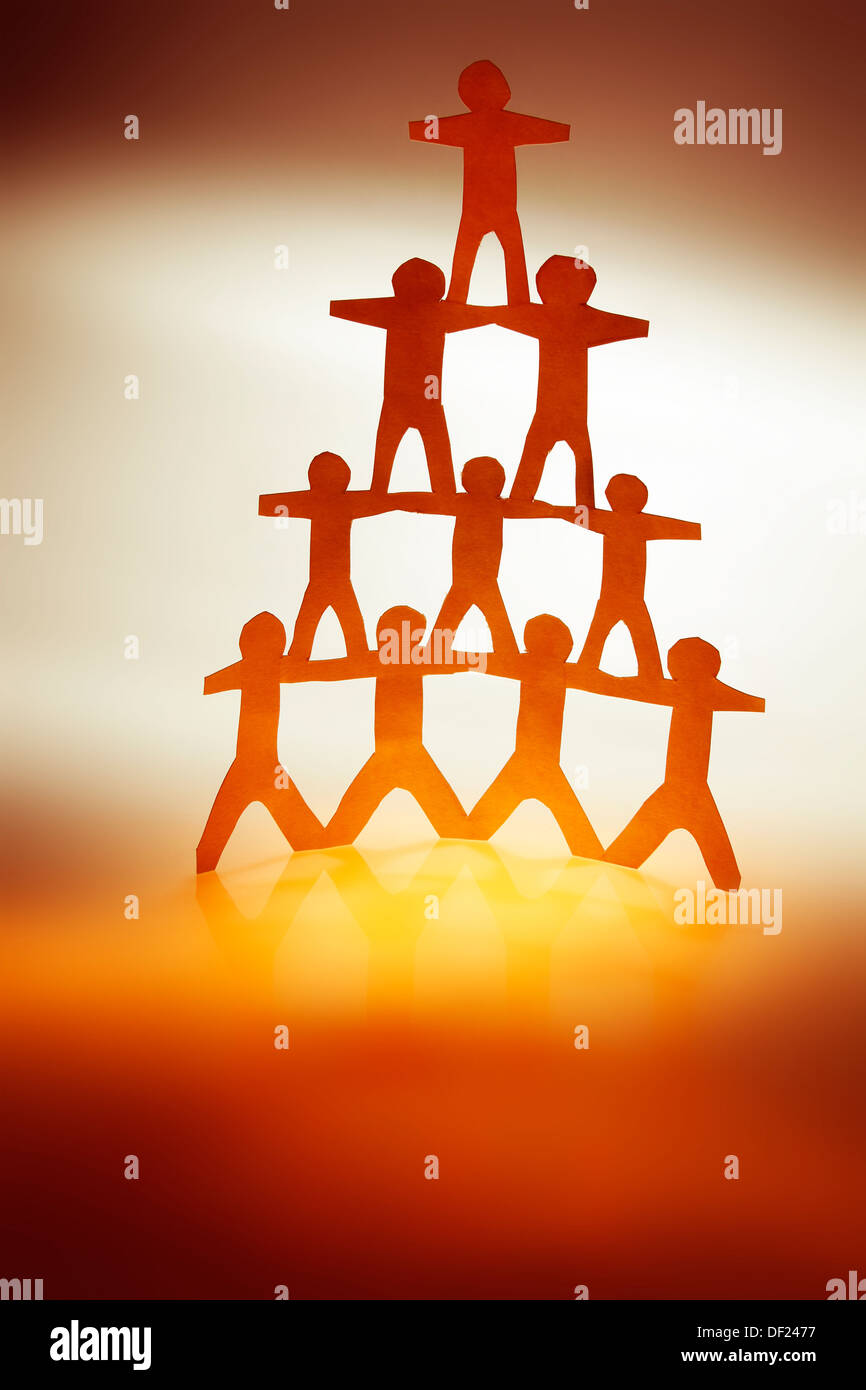Human team pyramid on orange background Stock Photo - Alamy
