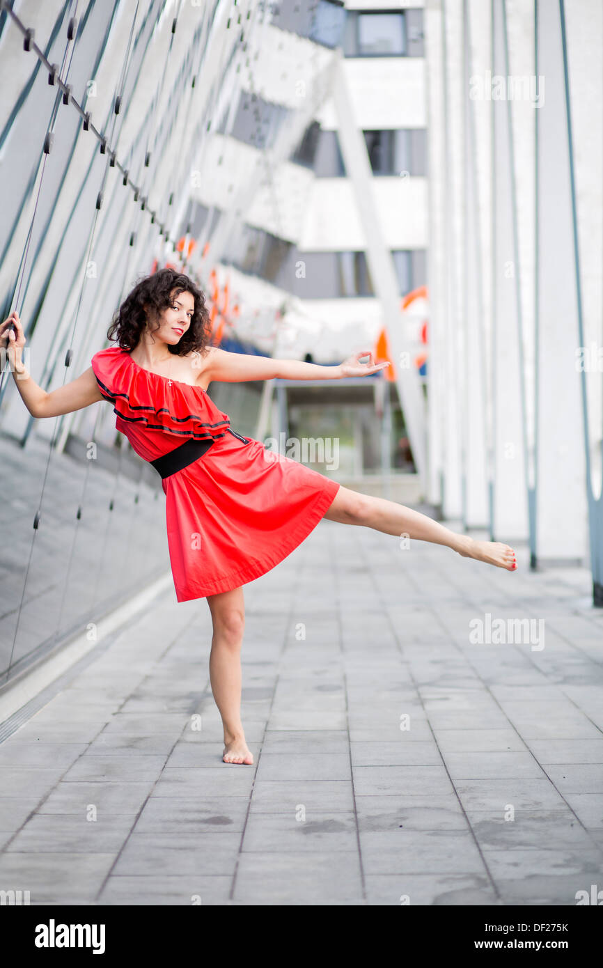 Woman in red dress posing on one leg Stock Photo - Alamy