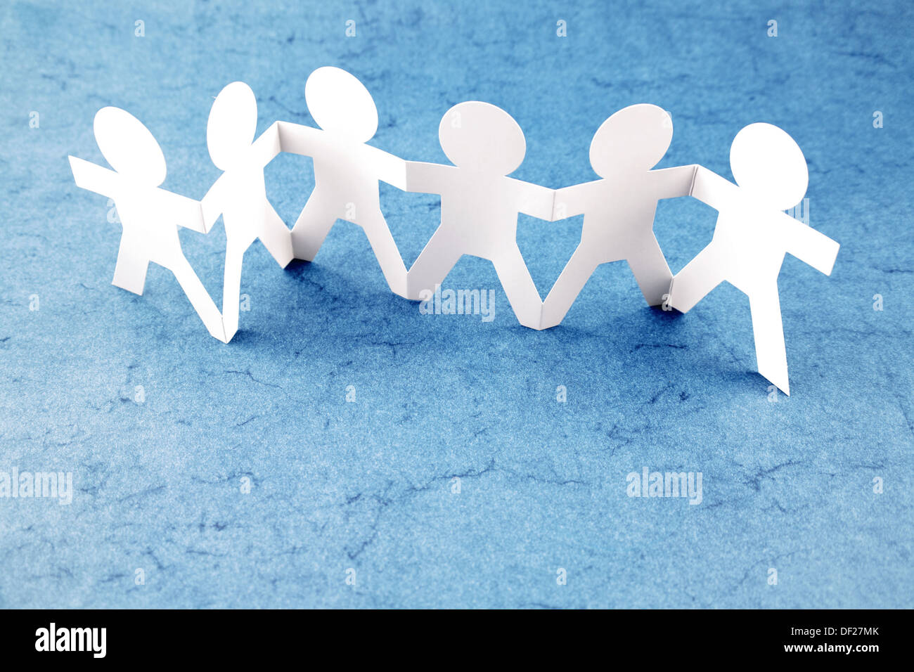 Group of paper chain people holding hands together. Teamwork concept Stock Photo - Alamy