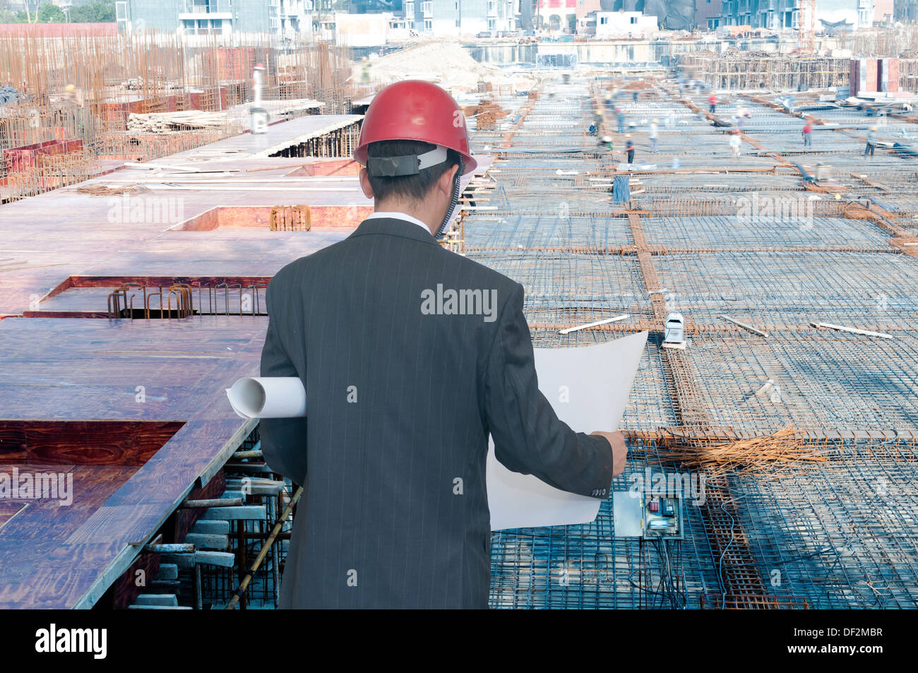 Rear view of architect looking comparing housing project with building ...