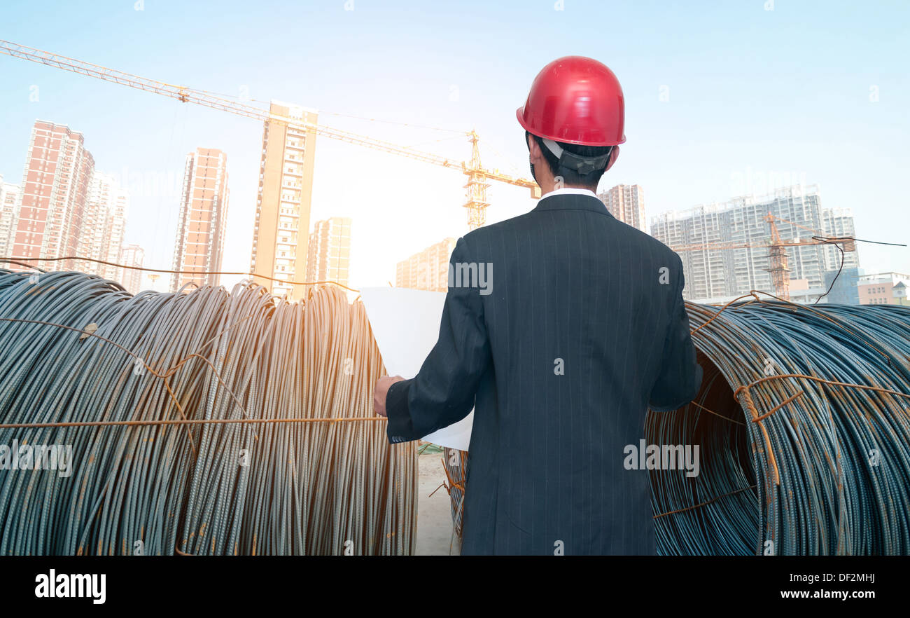 Rear view of architect looking comparing housing project with building ...