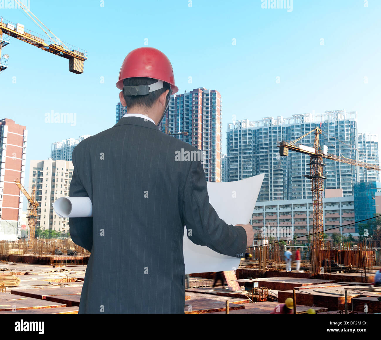Rear view of architect looking comparing housing project with building ...