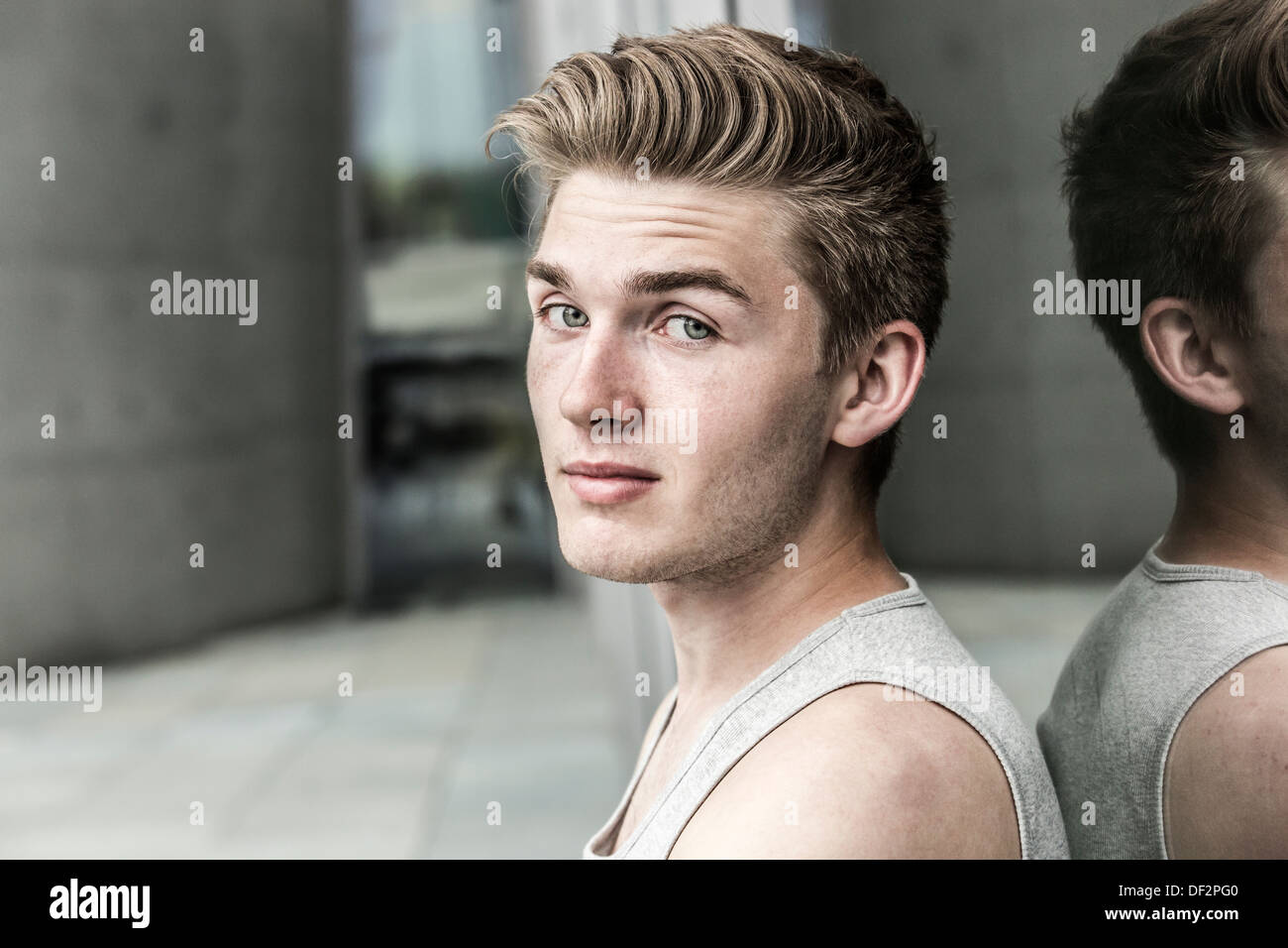 Young man leans against window of modern building Stock Photo - Alamy