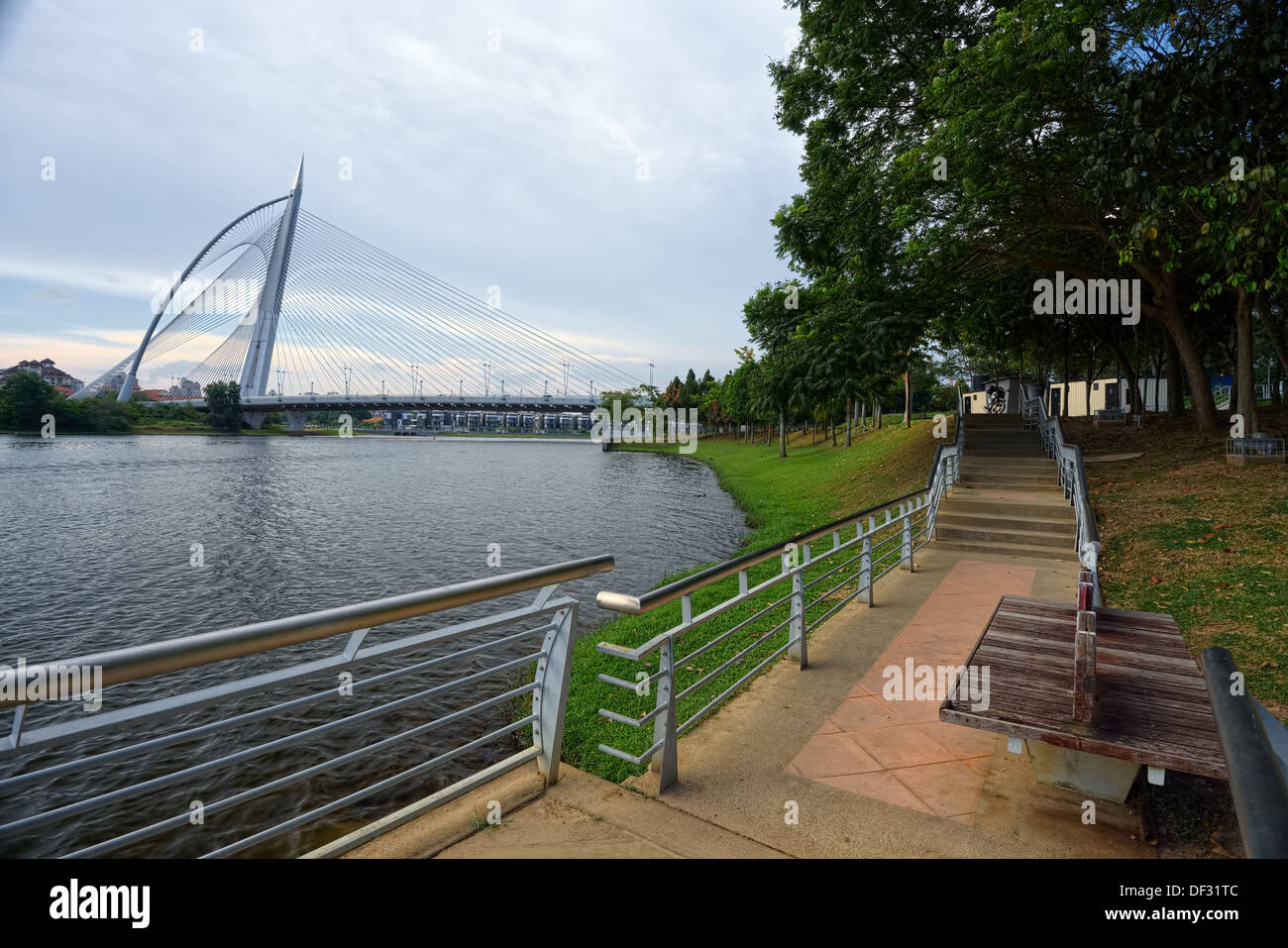 Walkway and bench beside lake and river with bridge at background Stock ...