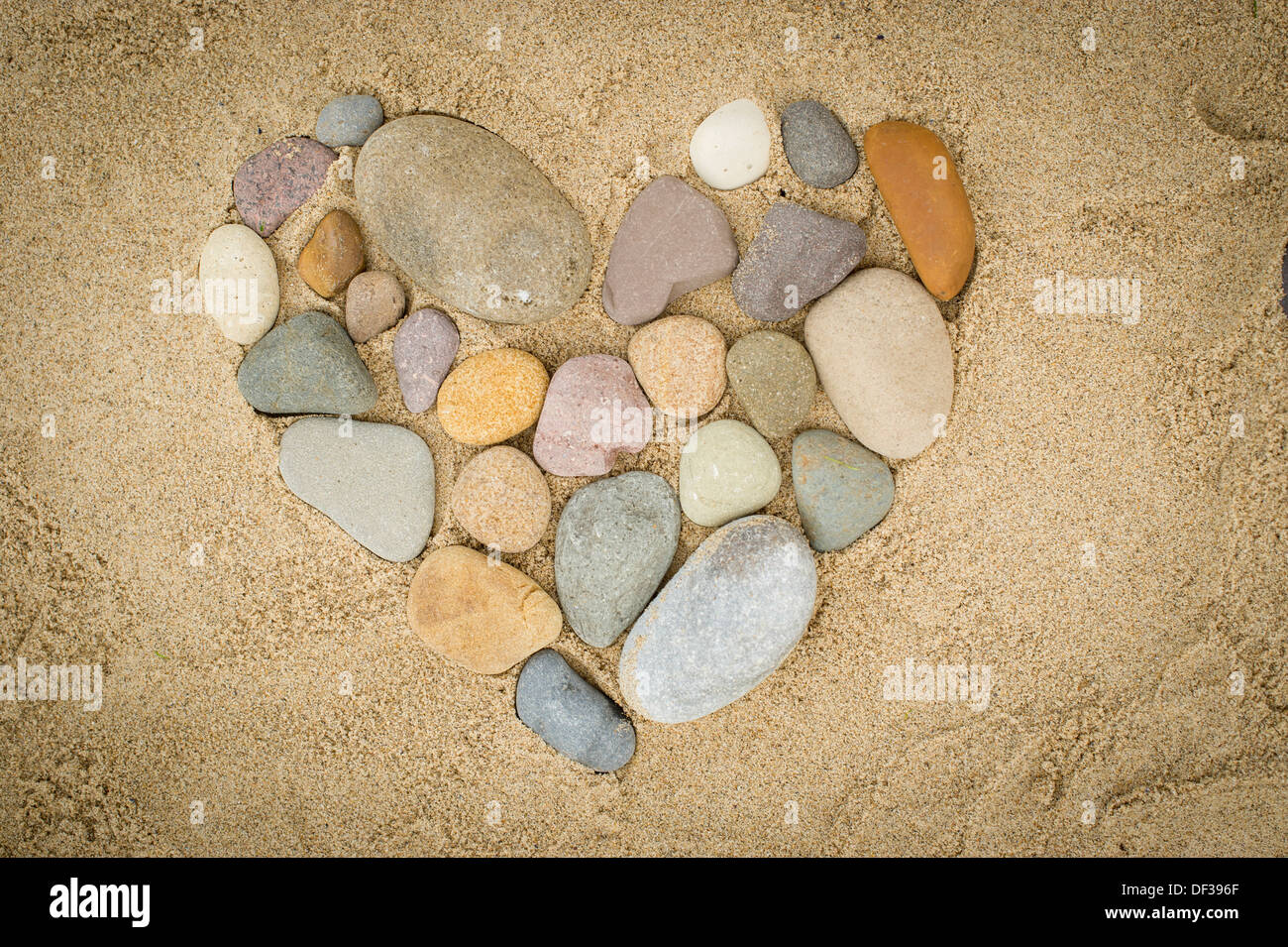 Pebbles arranged in a heart shape on a sand beach Stock Photo - Alamy