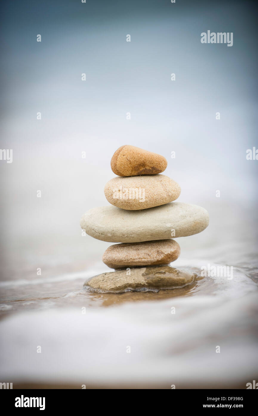 Five stones balanced on top of eachother as the tide comes in and wraps ...