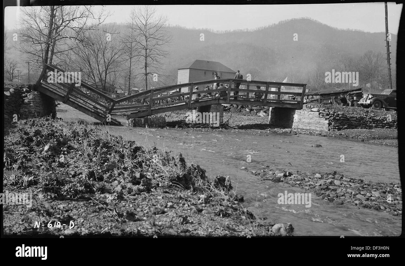 This photograph depicts a bridge damaged by flooding, capturing the ...