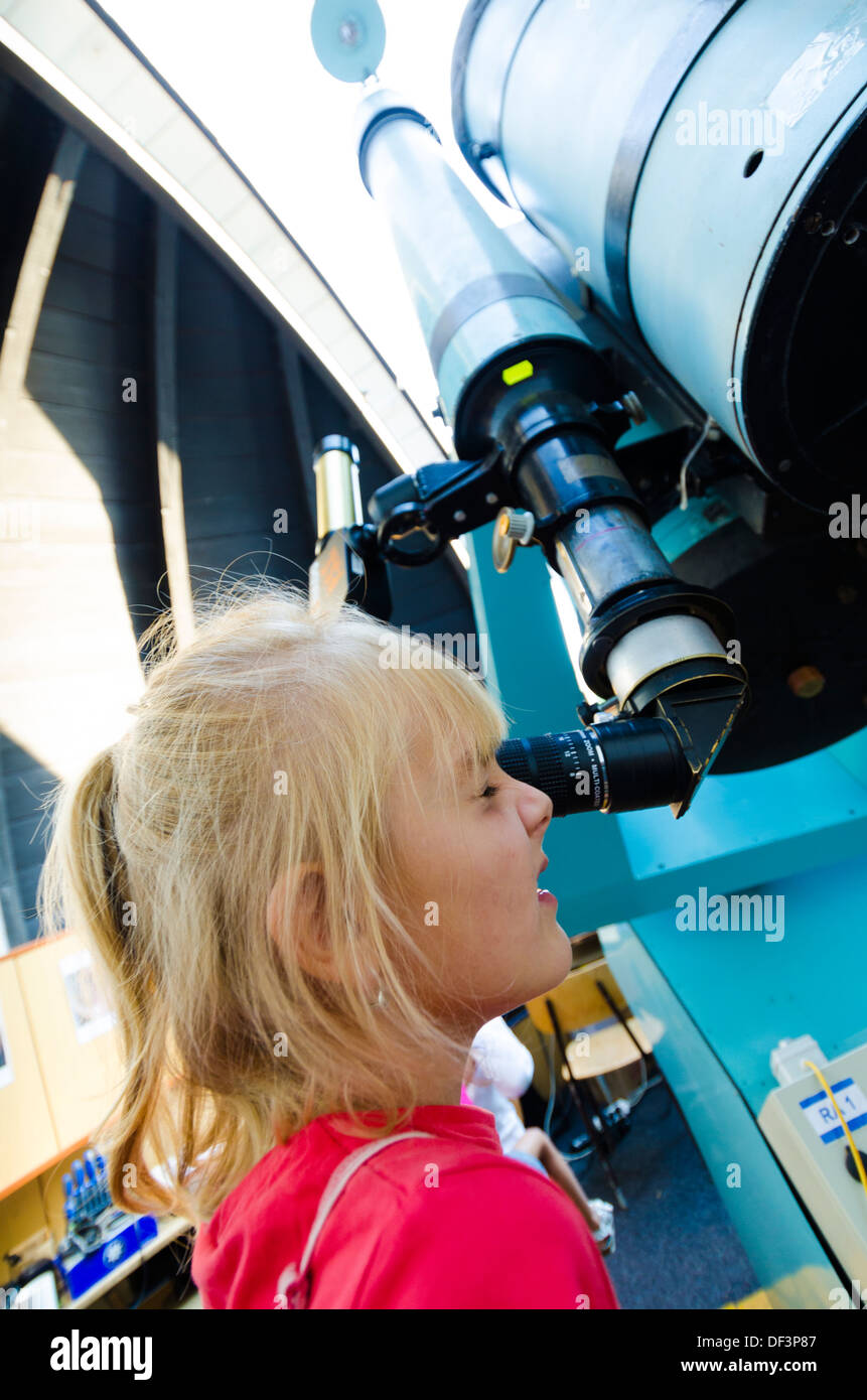 young girl looking through telescope, observing space objects Stock ...
