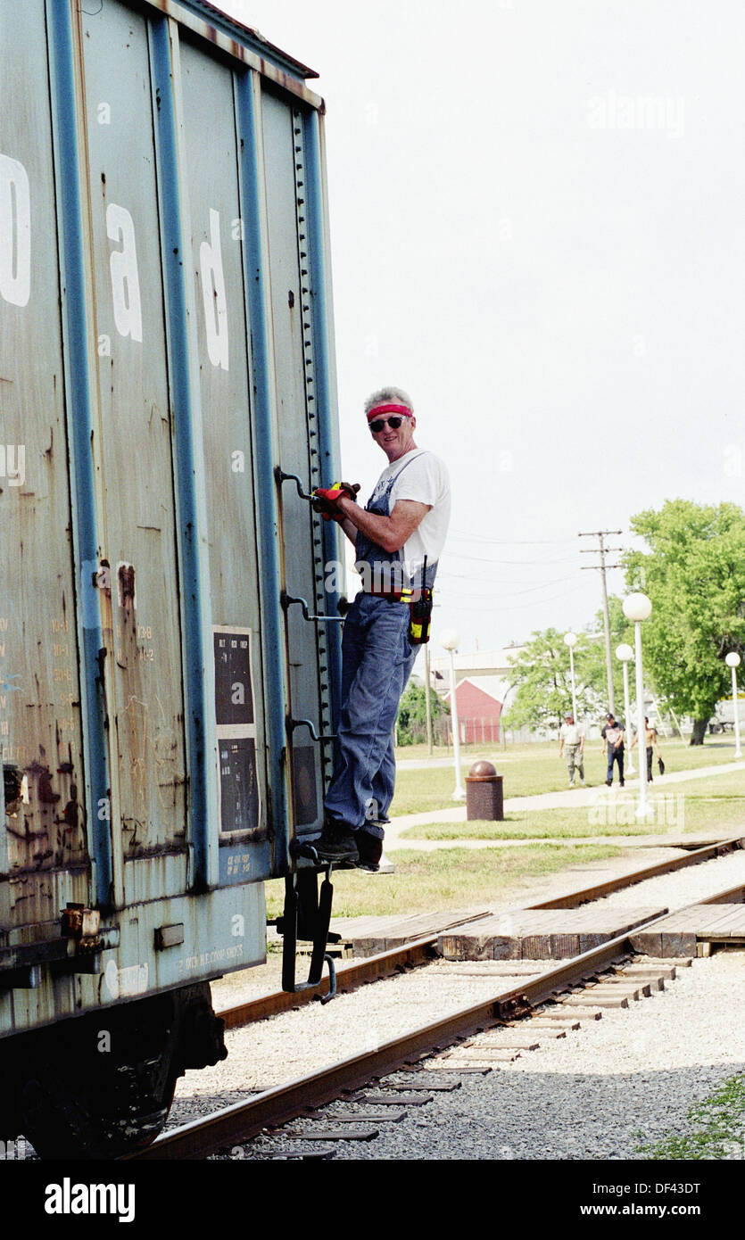 Train works its way slowly along the track with a worker standing on a ...