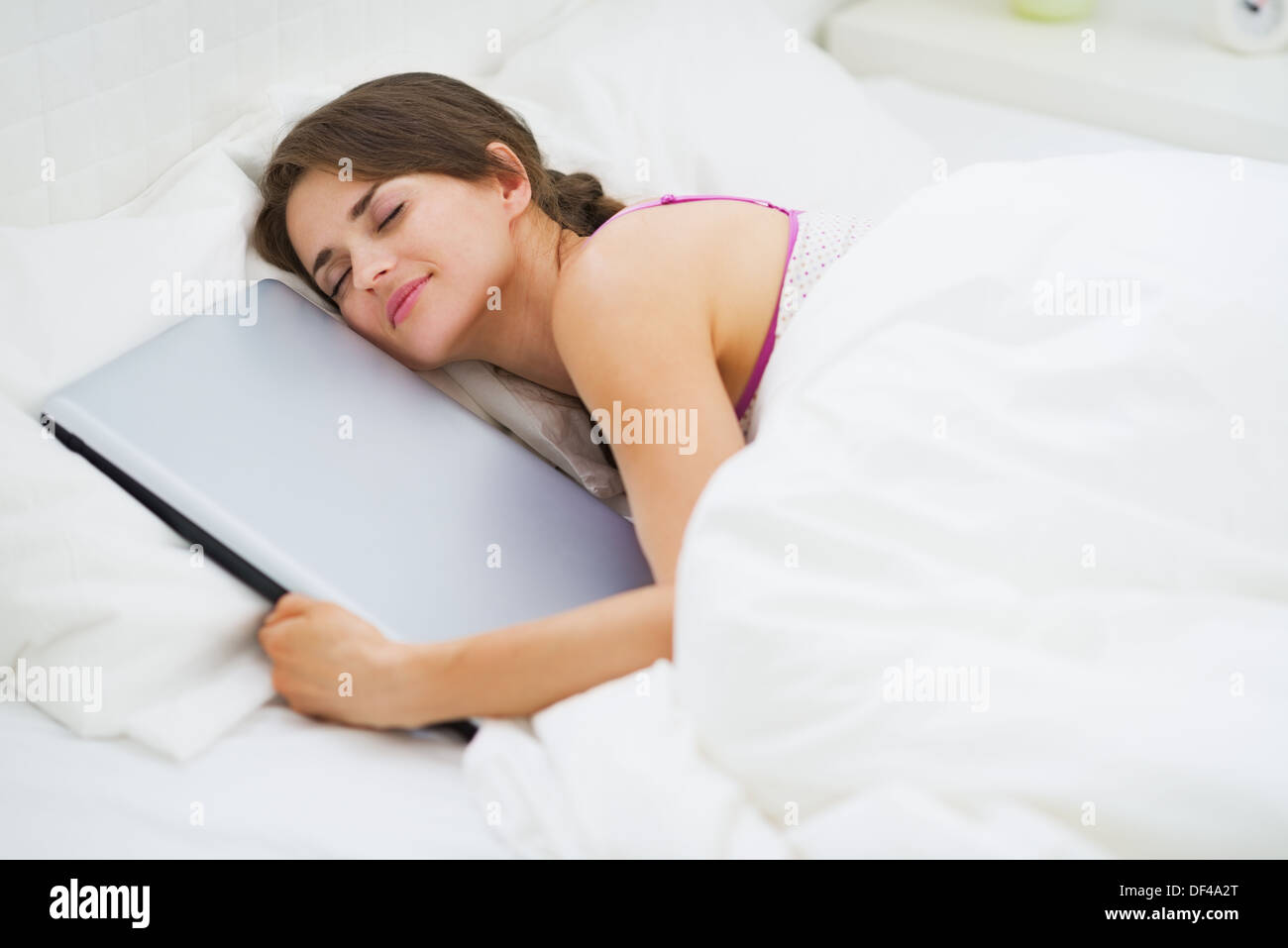 Young woman hugging laptop while sleeping Stock Photo - Alamy