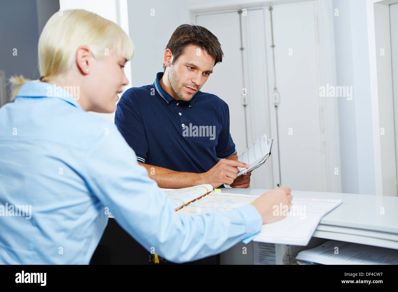 Man with appointment book scheduling an appointment at reception of ...