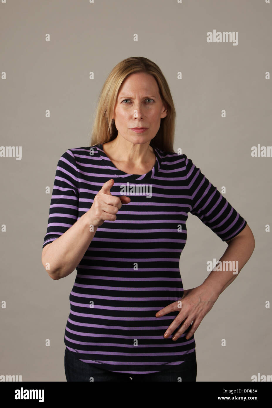Stern and serious attractive middle aged woman pointing and looking at ...