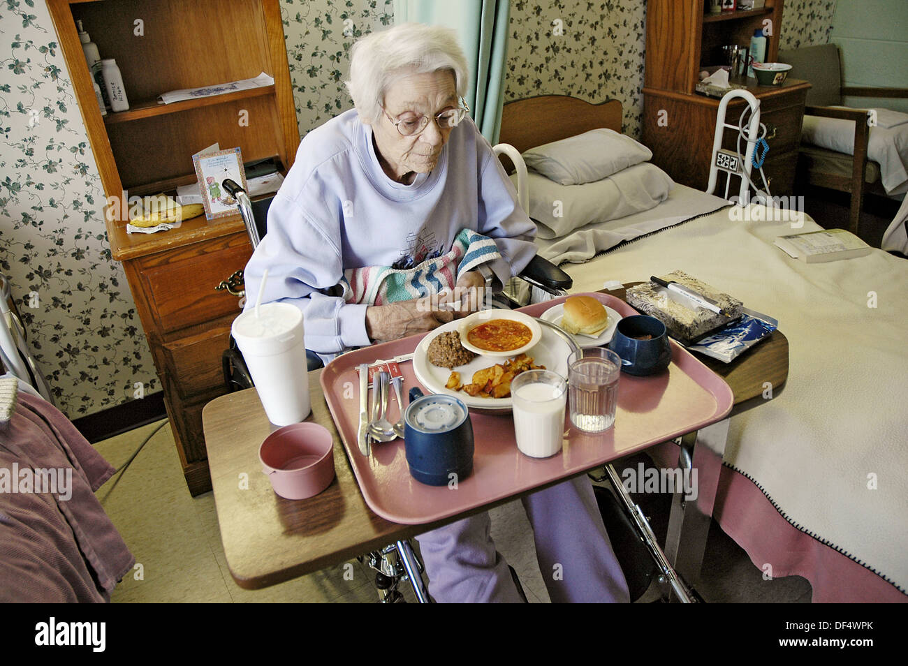 A senior female receives assistance by being served food and meals in ...