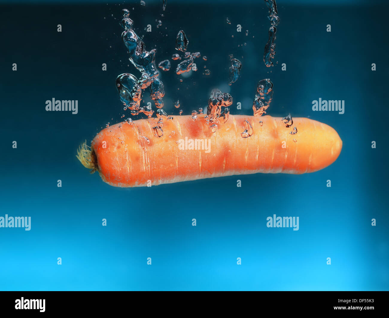 Carrot in the water splash over blue background. Healthy food and ...