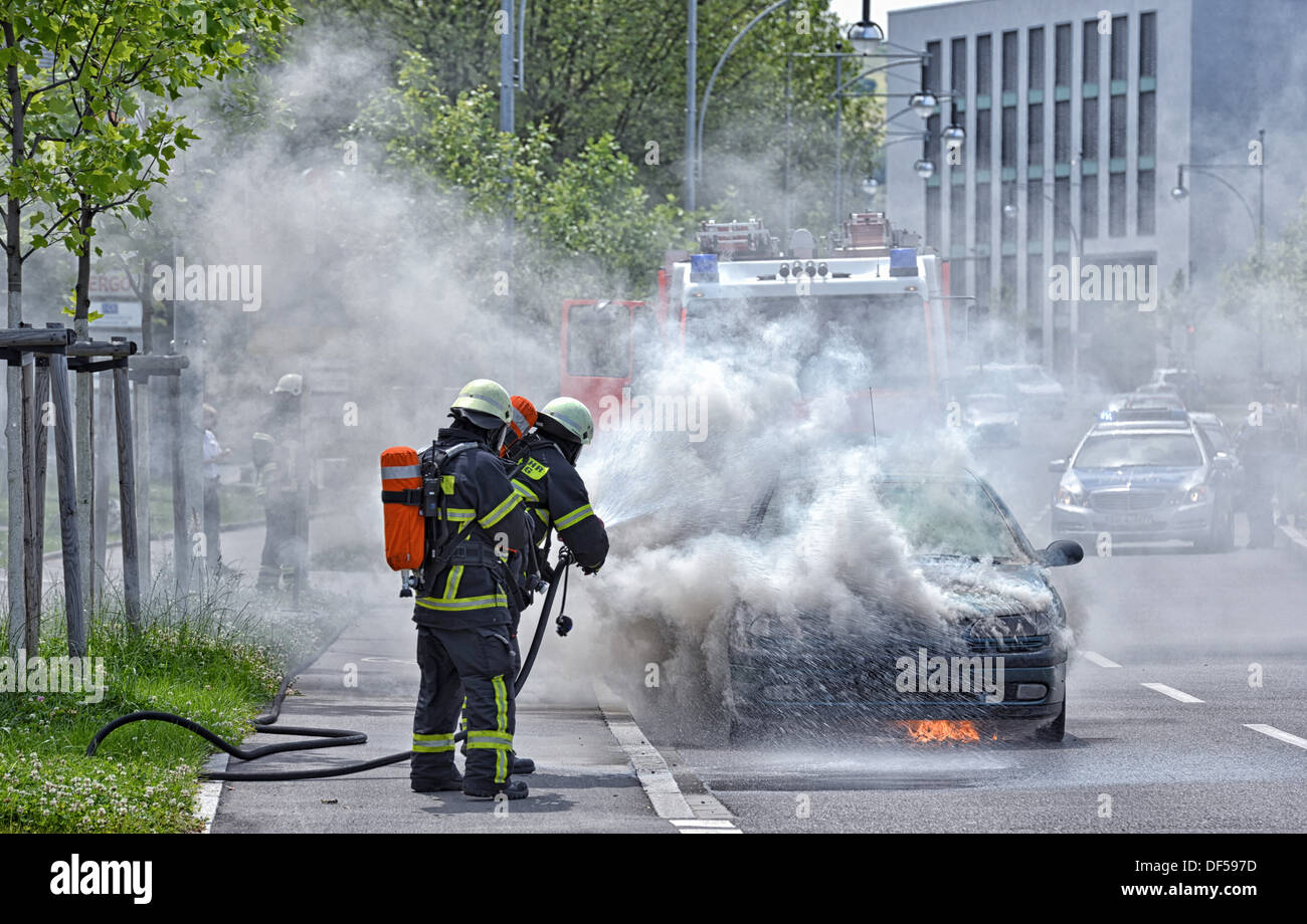 Firefighters are just putting out a burning and smoking car on the ...