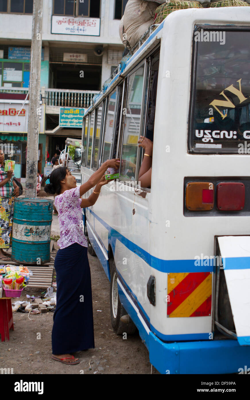 A vendor makes a sale to a bus occupant at a bus station in Mandalay ...