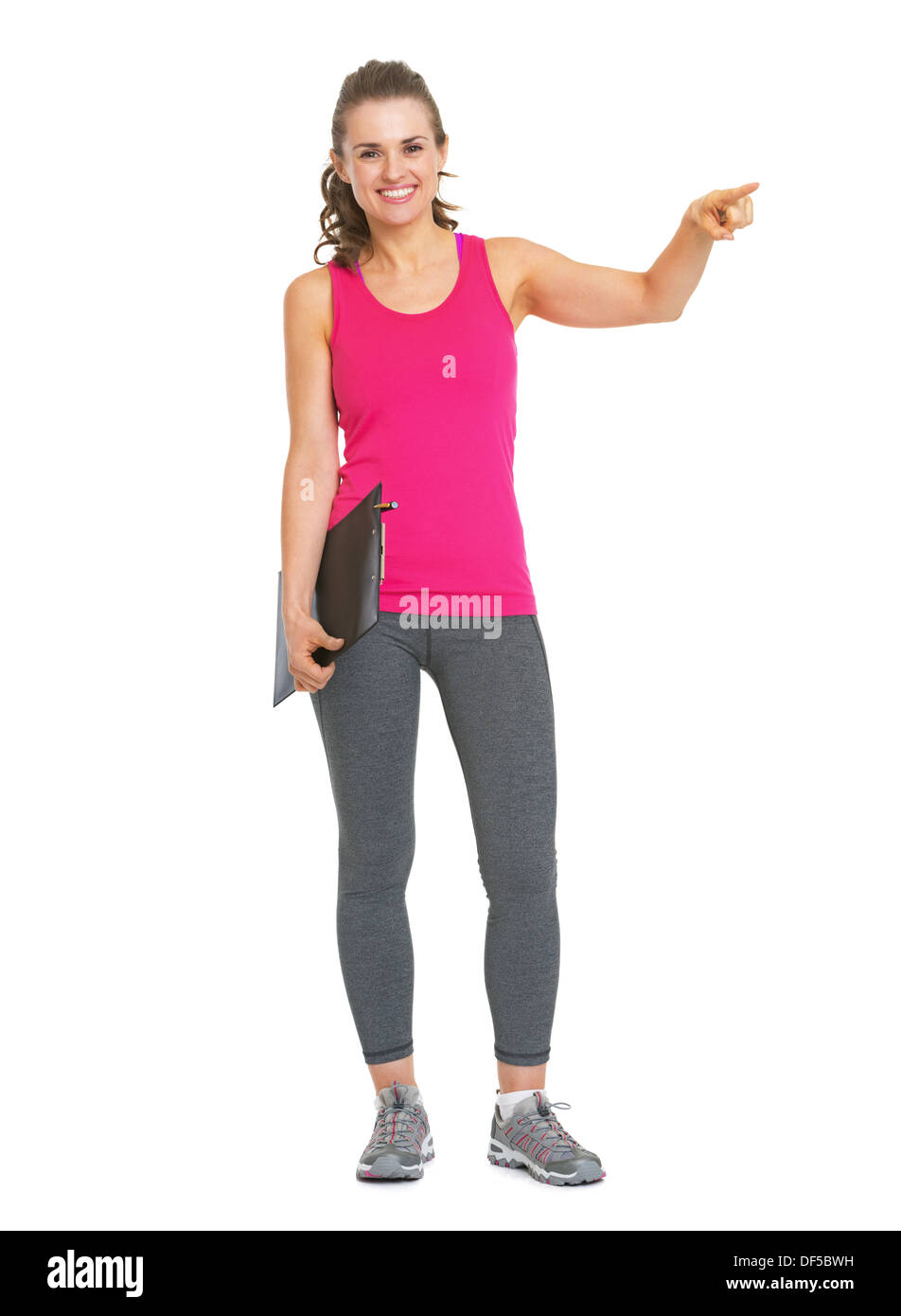 Full length portrait of smiling fitness trainer with clipboard pointing ...